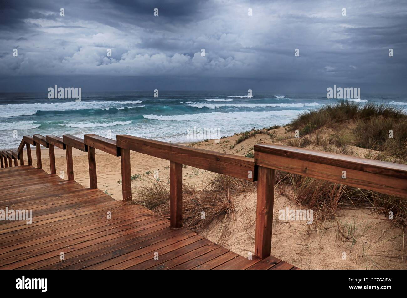 Wooden pathway on the beach by the breathtaking ocean waves under the ...