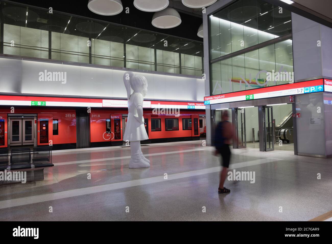 Train arriving on the station Tapiola of Helsinki metro. Statue Emma ...