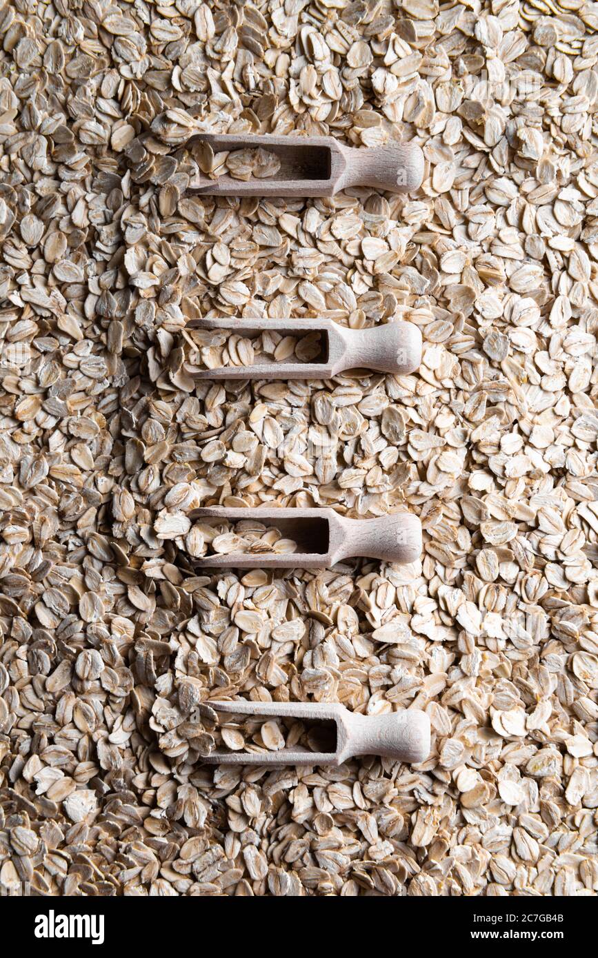 Four wooden scoops with flakes of rolled oats in them. Row of scoops is ...
