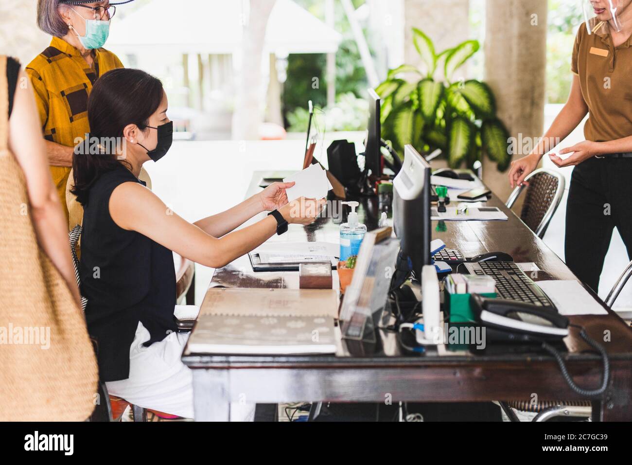 Selected focus receptionist with face shield giving envelope to guest ...