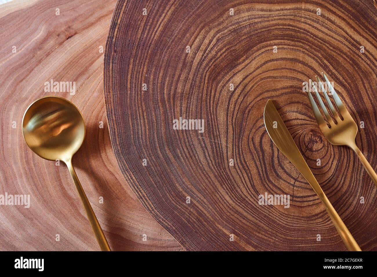 The golden spoon, knife and fork lies on a slice of a tree. wooden ...
