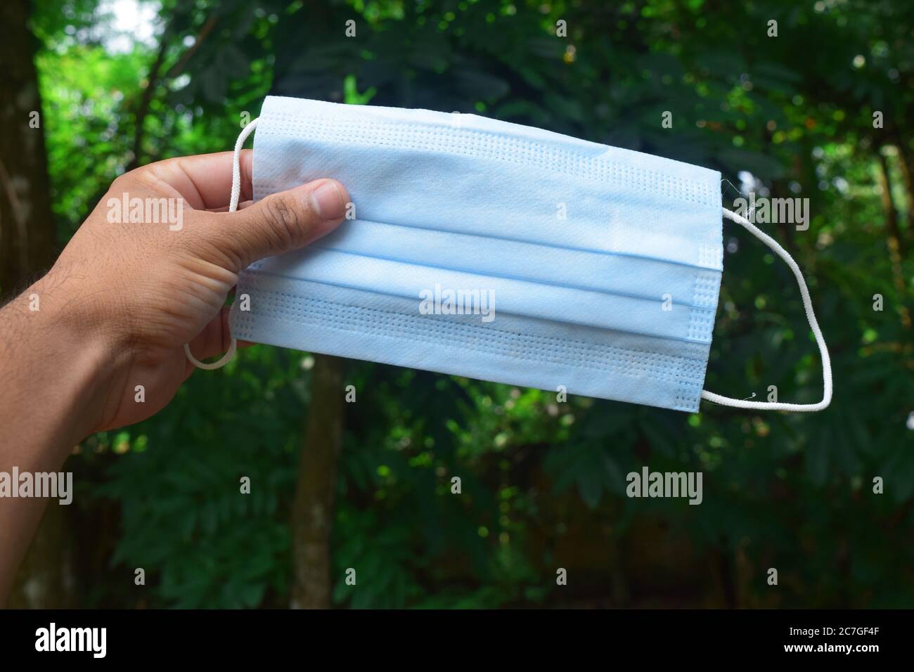 Medical surgical face mask on hand front of green nature background ...