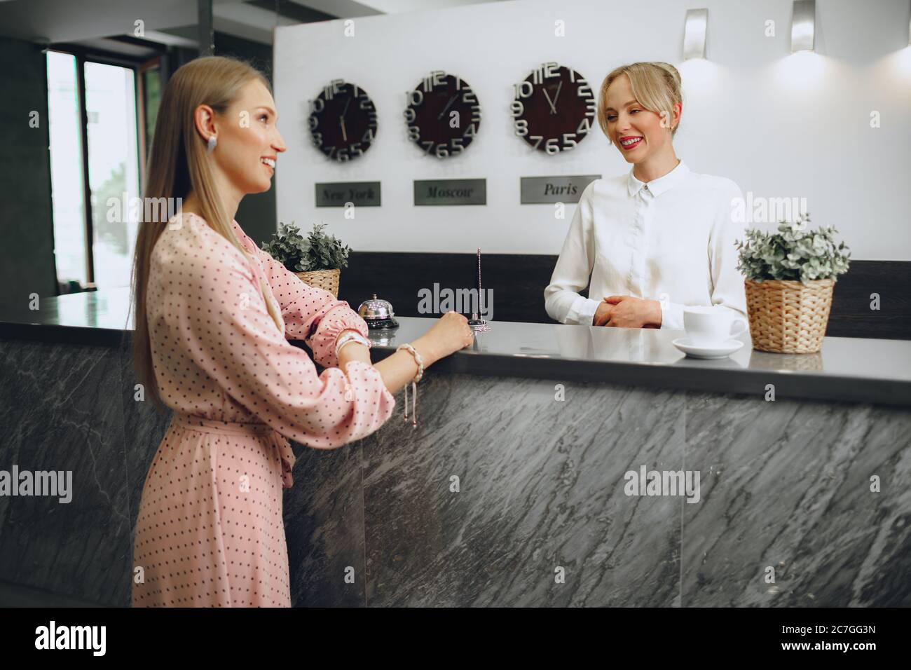 Blonde woman hotel guest checking-in at front desk in hotel Stock Photo ...