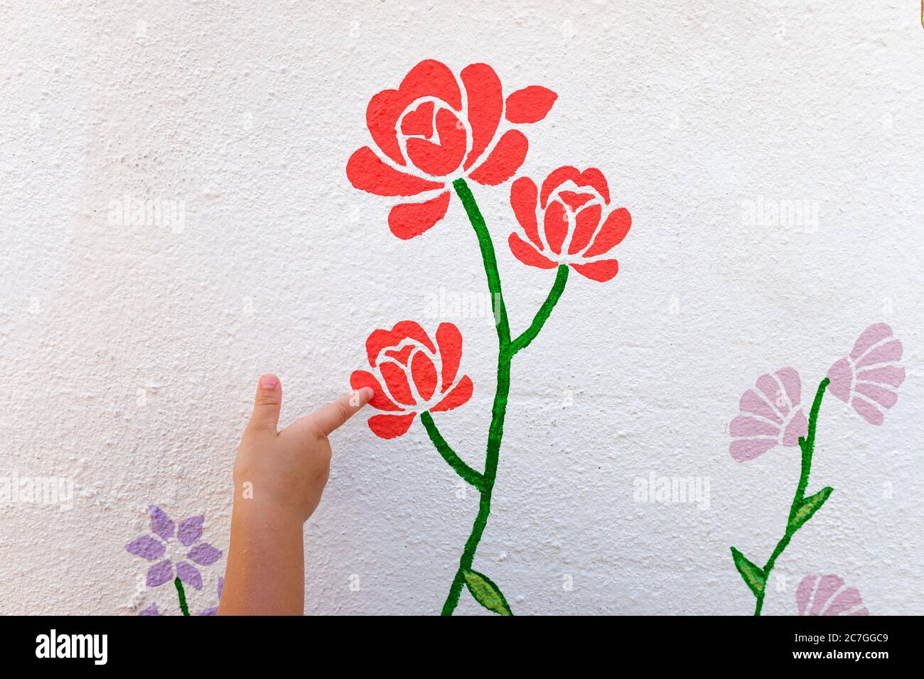 Girl pointing her finger at a drawing of a painted flower on the white ...
