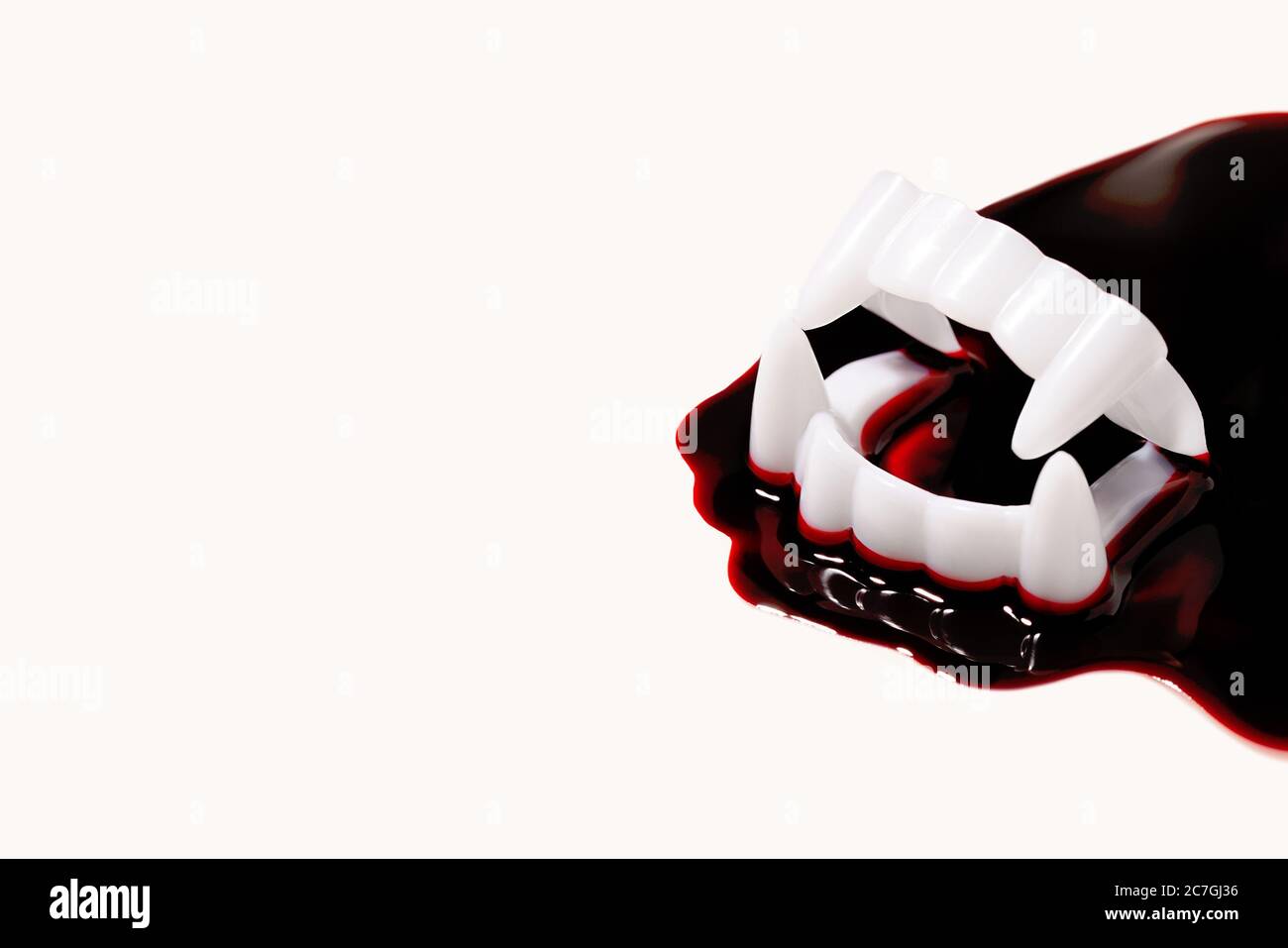 Vampire Dracula toy teeth with pool of fake blood on white background ...