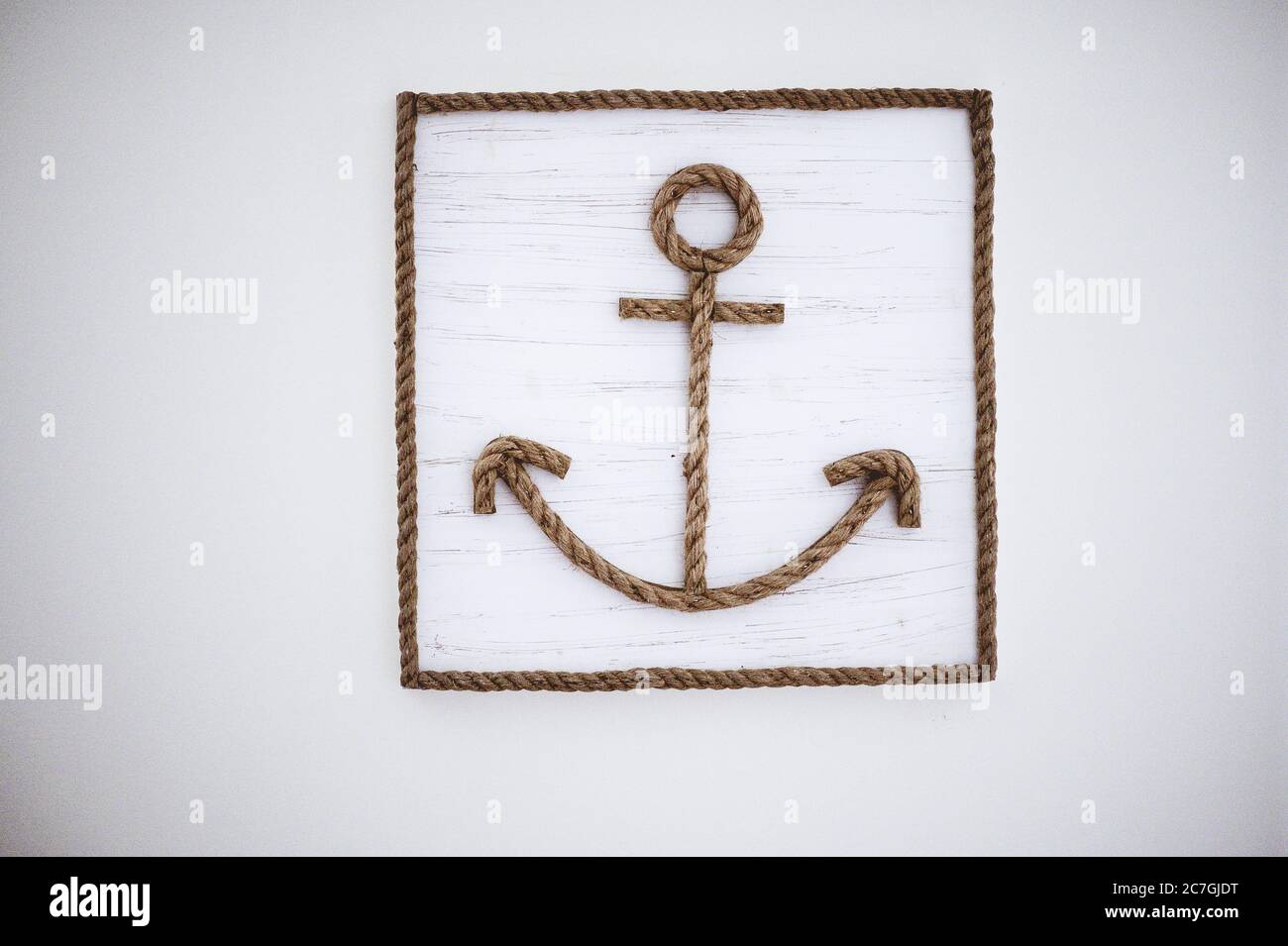 Anchor sign made from ropes on a white wooden wall Stock Photo - Alamy