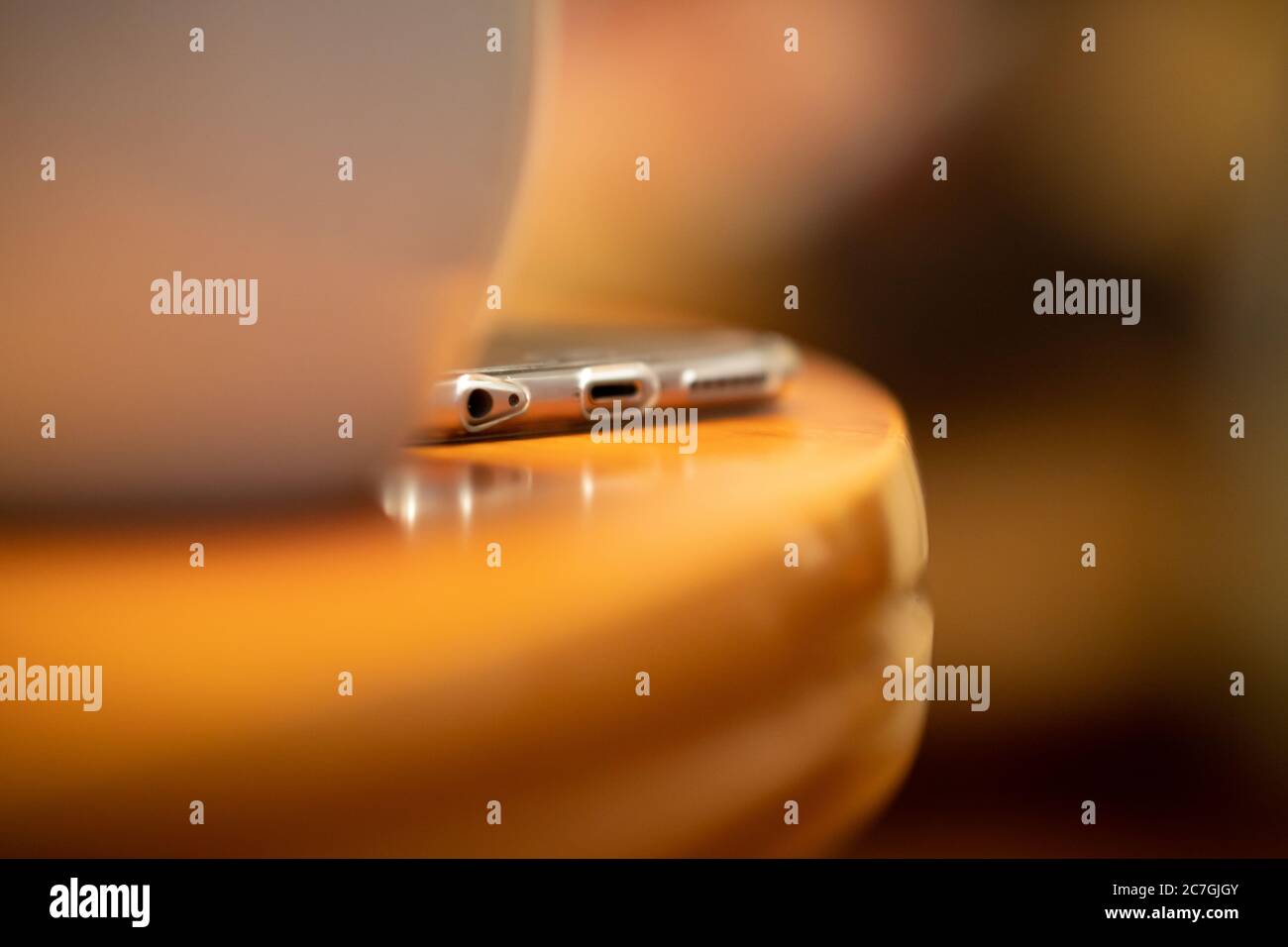 Selective focus closeup of a bottom of phone on wooden table with ...