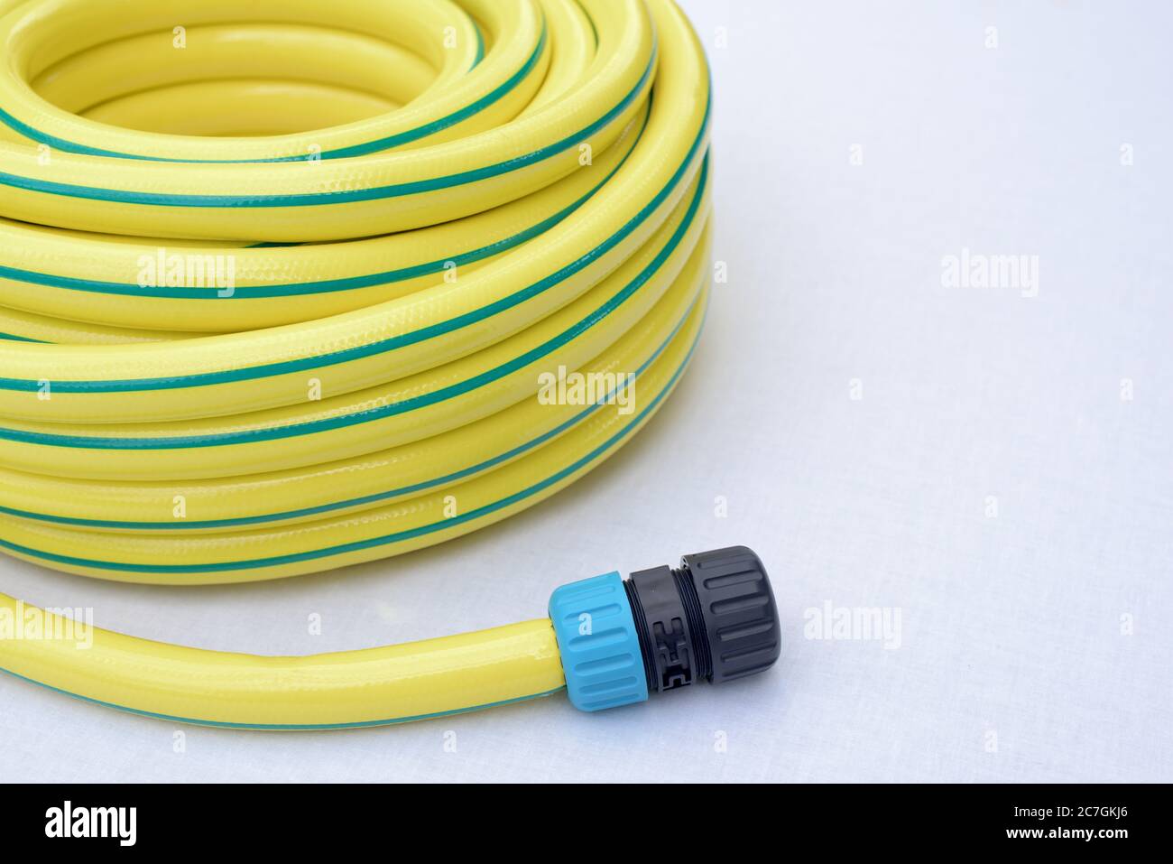 Plastic yellow rolled up hose pipe with connector on white background ...