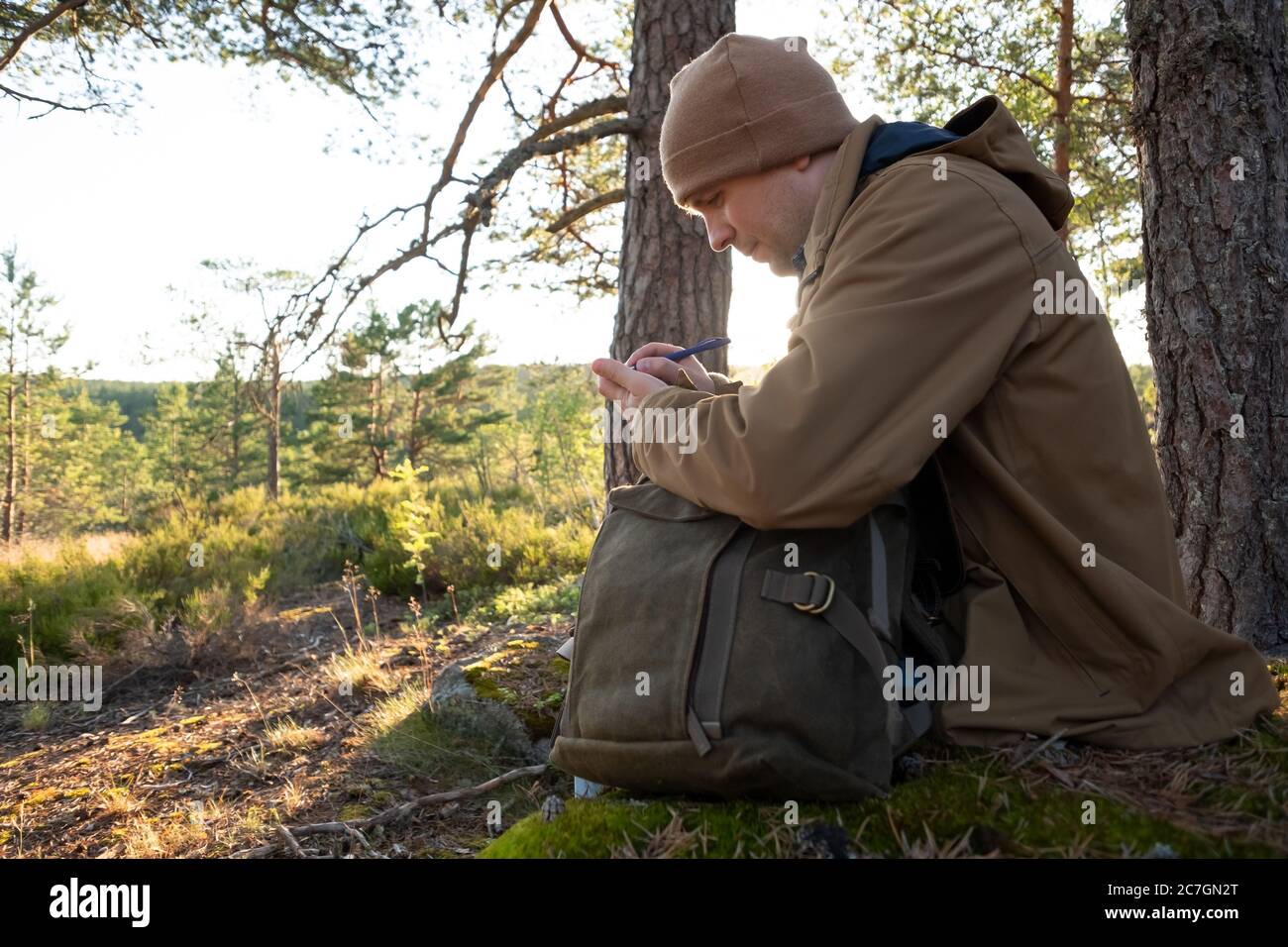 man in forest sits on the ground, writing something in diary Stock ...