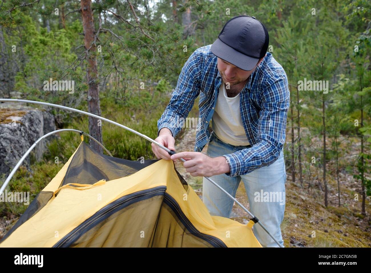 Male tourist making a tent at forest camp Stock Photo - Alamy