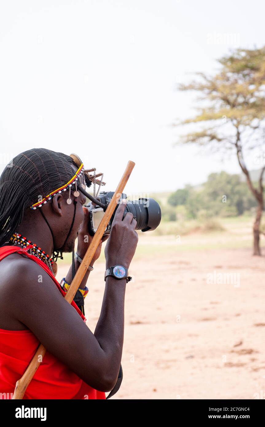 Maasai man smiling wearing traditional attire, taking photographs ...