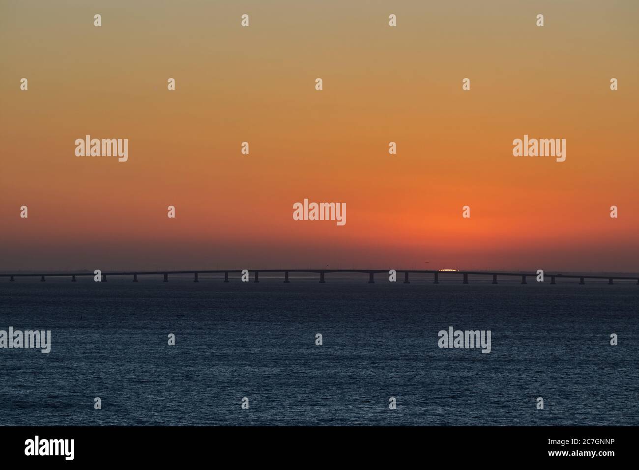 Breathtaking sunset behind a bridge over the beautiful calm ocean Stock ...