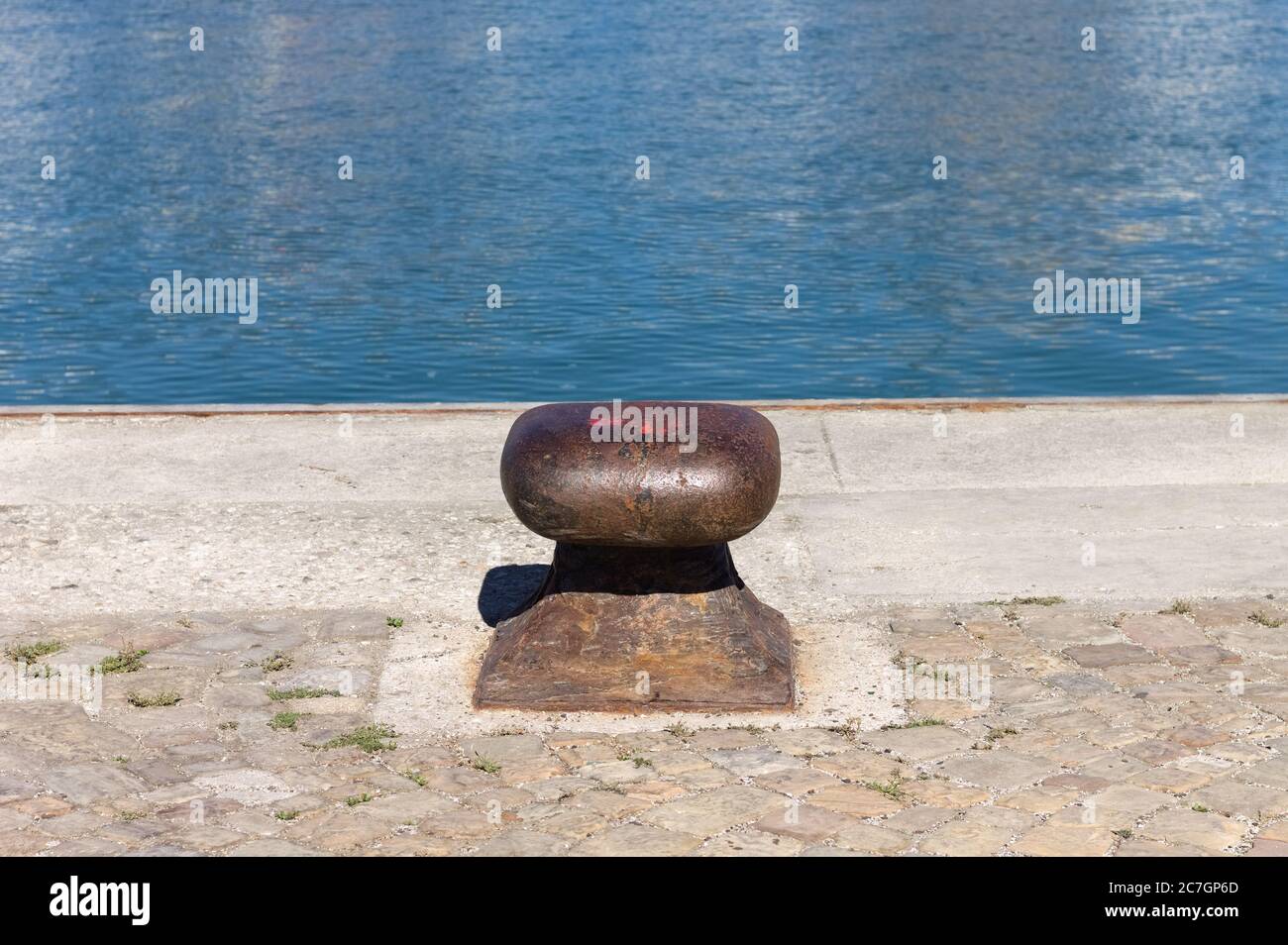Isolated rusted mooring bollard on the jetty of a commercial dock ...