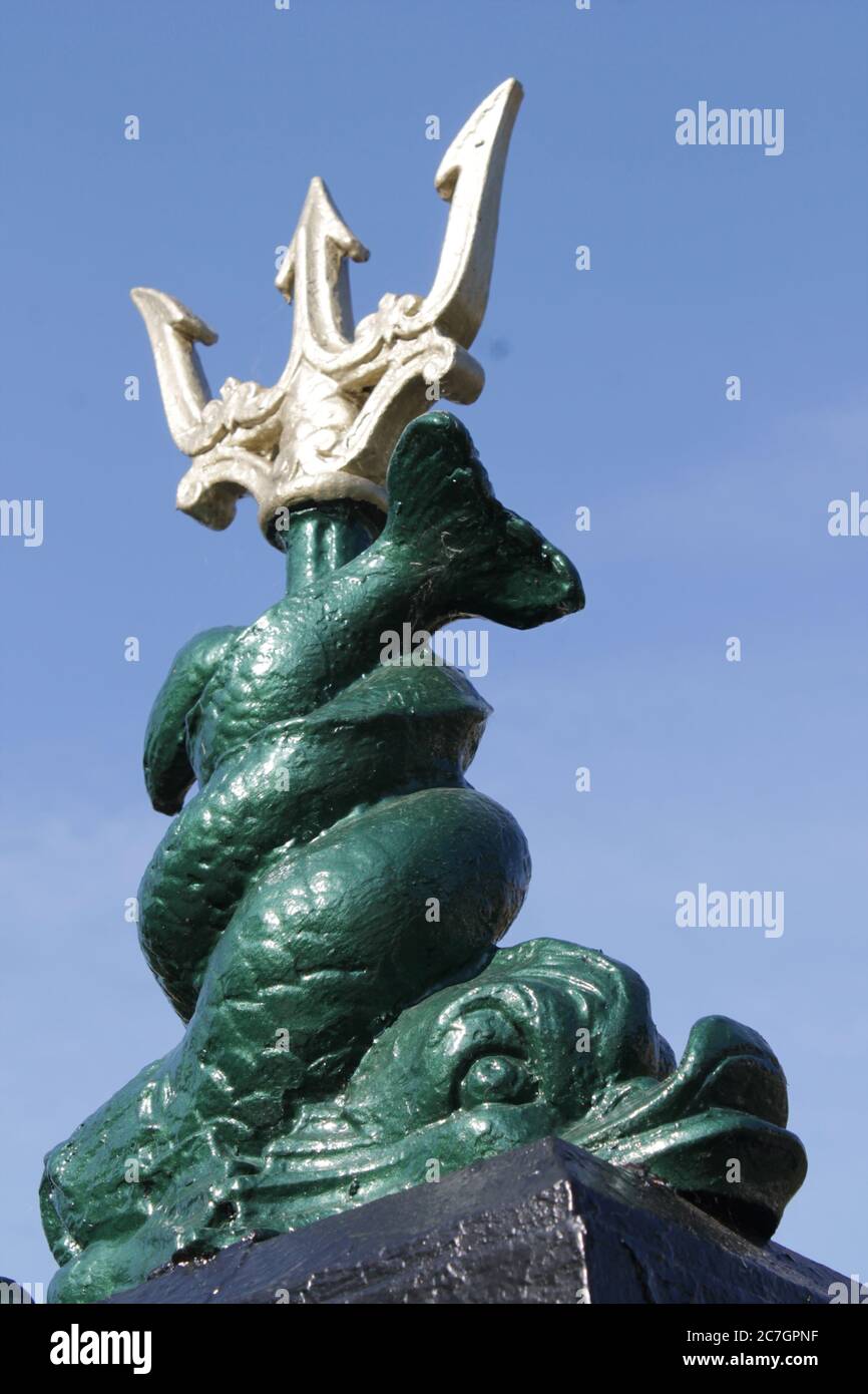 Vertical low angle shot of a trident wrapped in a fish statue with a ...