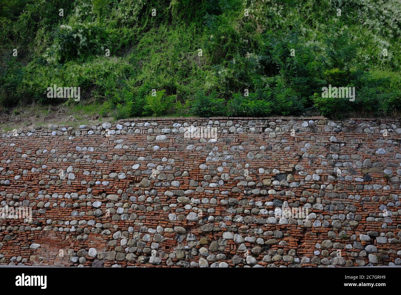 a stone and brick wall under trees Stock Photo - Alamy
