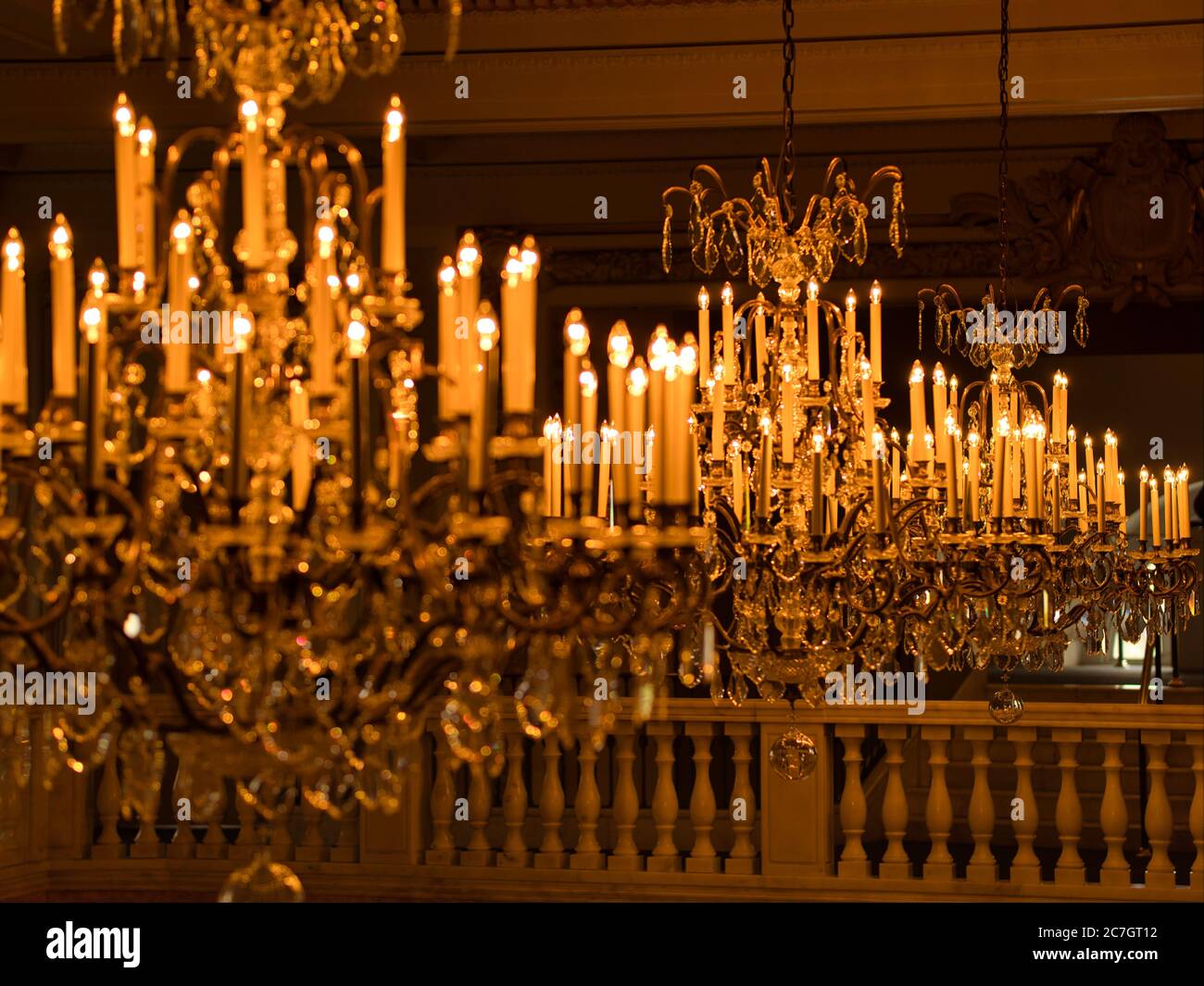 Beautiful chandelier with the lights on in a building with a balcony ...