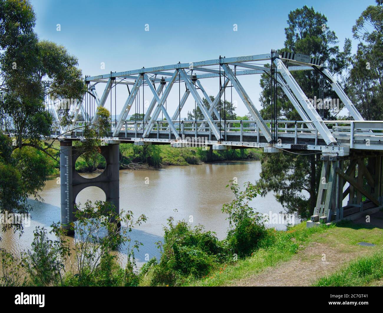 Truss bridge on a river surrounded by greenery under sunlight Stock ...