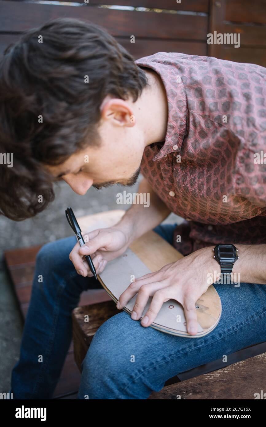 Concentrated man drawing skateboard using template and pen Stock Photo ...
