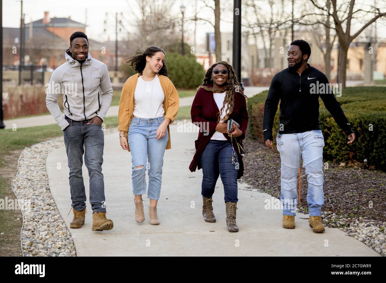 Group of friends walking happily on the sidewalk in a park Stock Photo ...