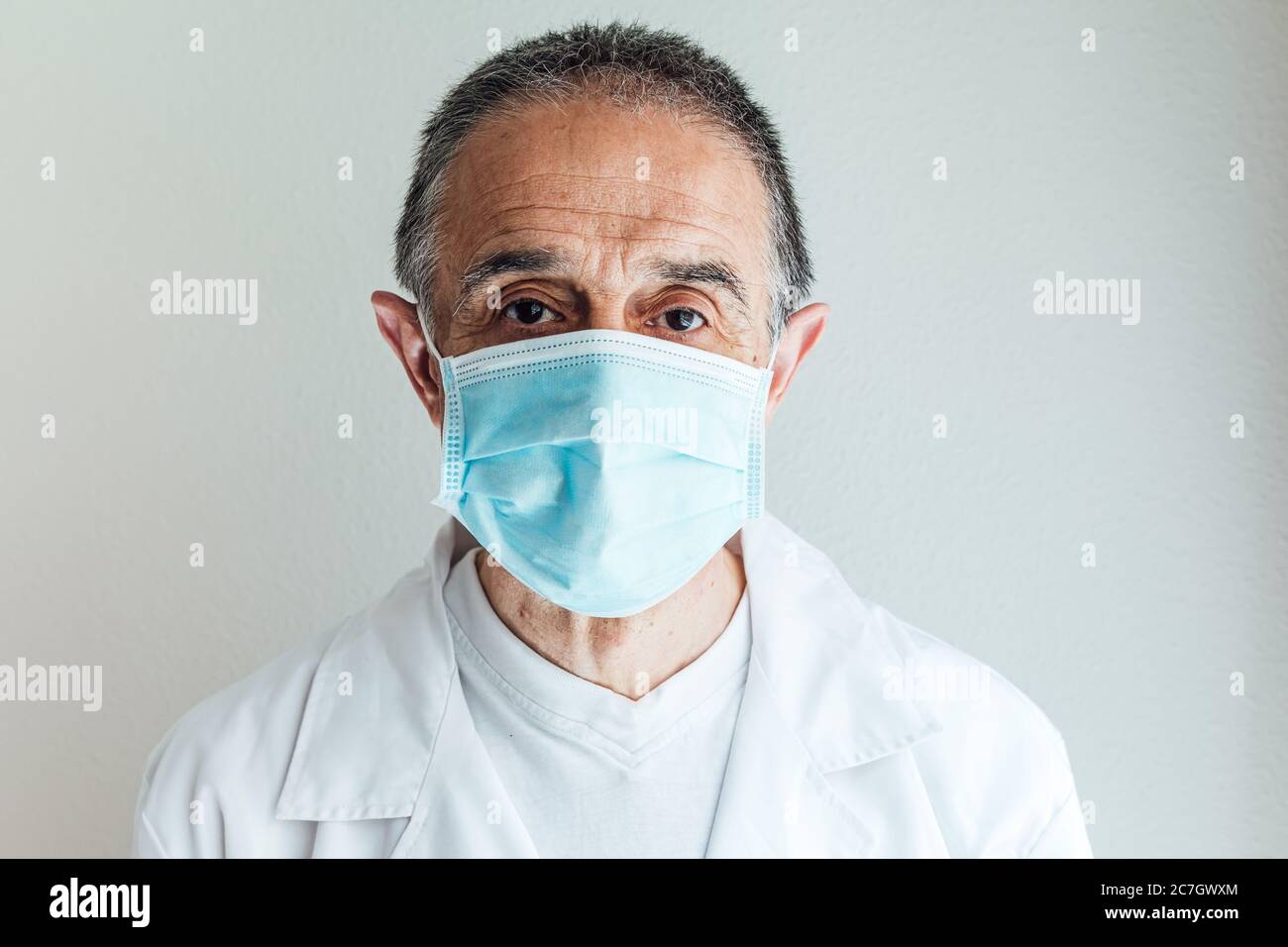 Portrait of doctor wearing white coat and surgical mask to protect ...