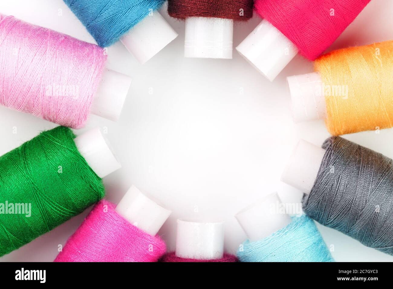 Sewing threads of different colors on reels on a white background in a ...