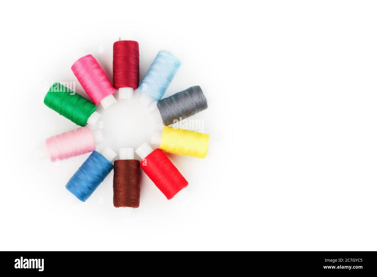 Sewing threads of different colors on reels on a white background in a ...