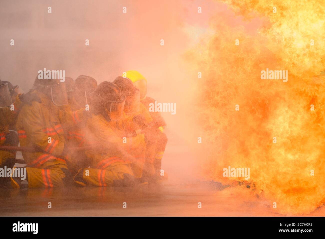 fireman fighting fire flame with water and extinguisher in training ...