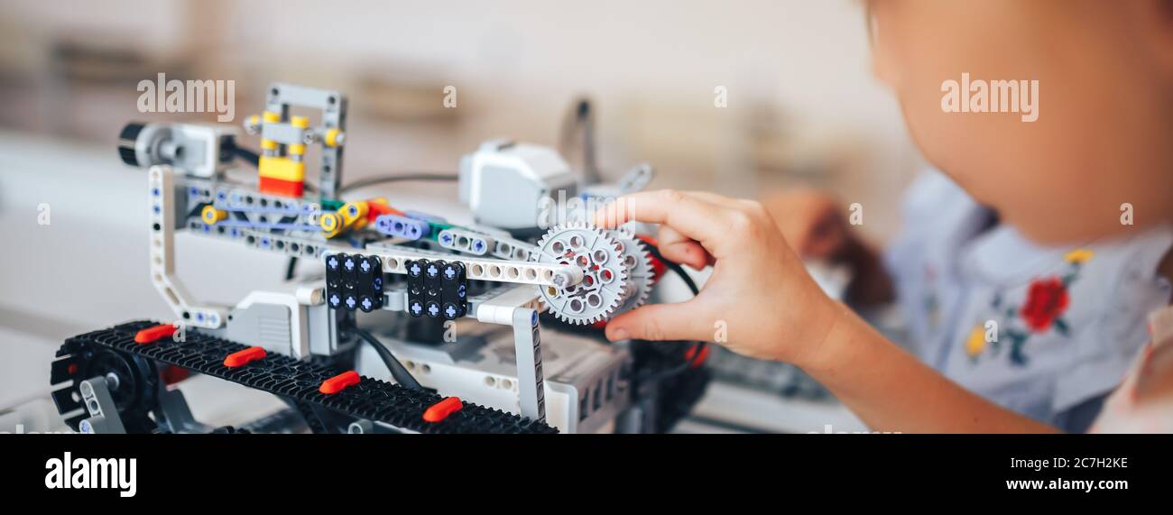 Two schoolgirls study in a robotics class, assemble a robot constructor ...