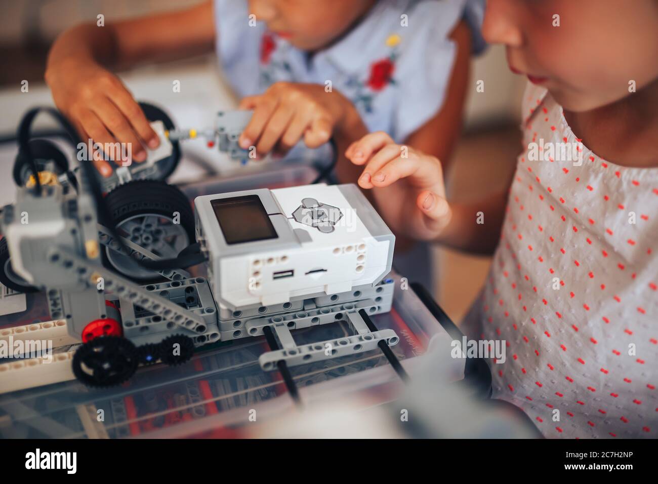 Two schoolgirls study in a robotics class, assemble a robot constructor ...