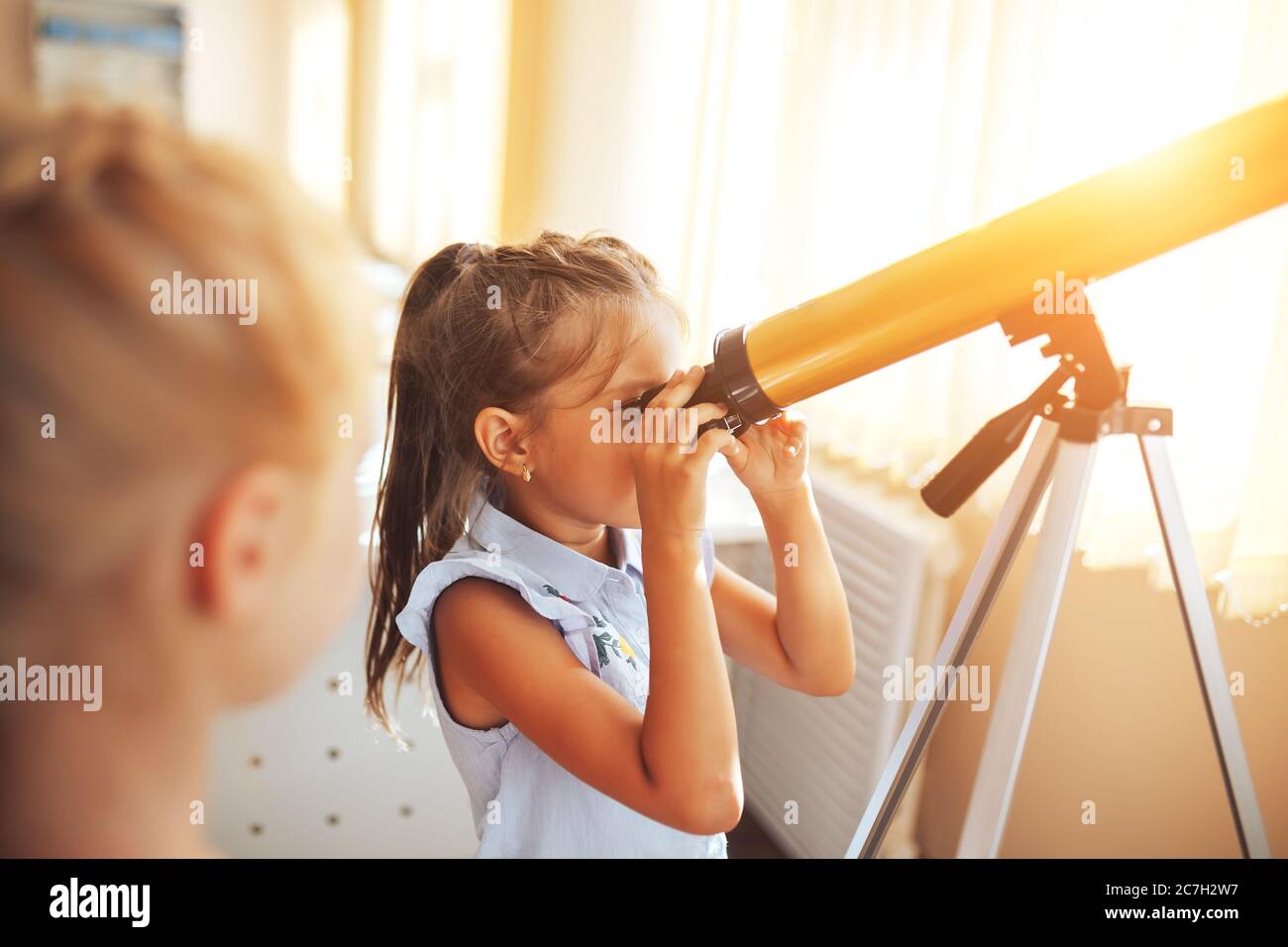 Two schoolgirls are looking through a telescope in an astronomy lesson ...