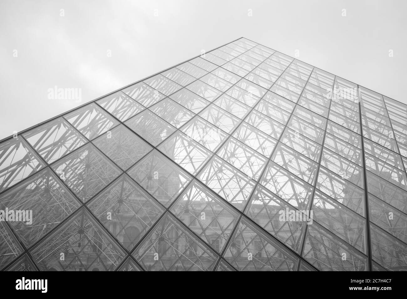 Low angle greyscale of the Louvre Museum under a cloudy sky in Paris in ...