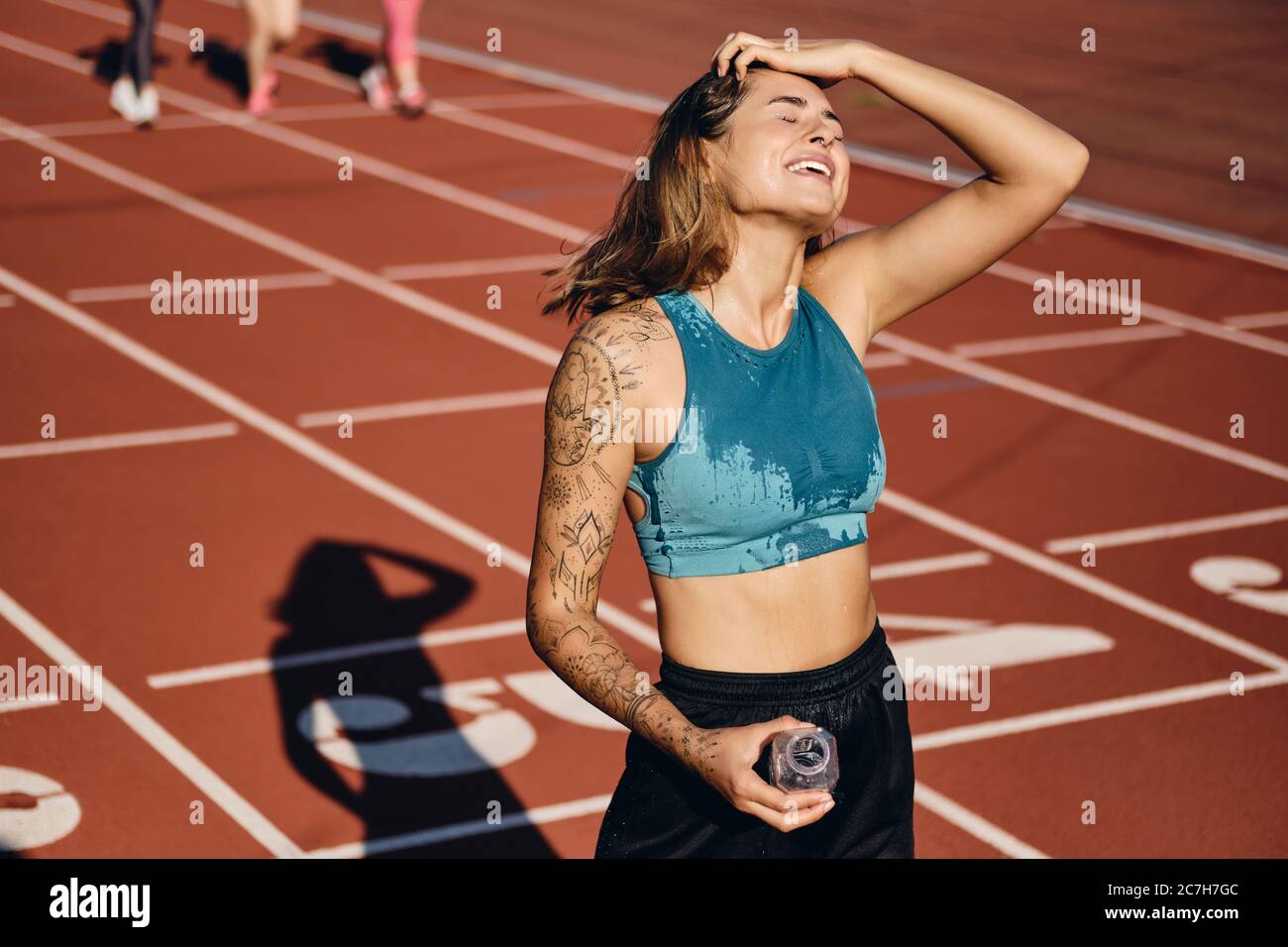 Cheerful wet athlete girl in sportswear happily resting after running ...