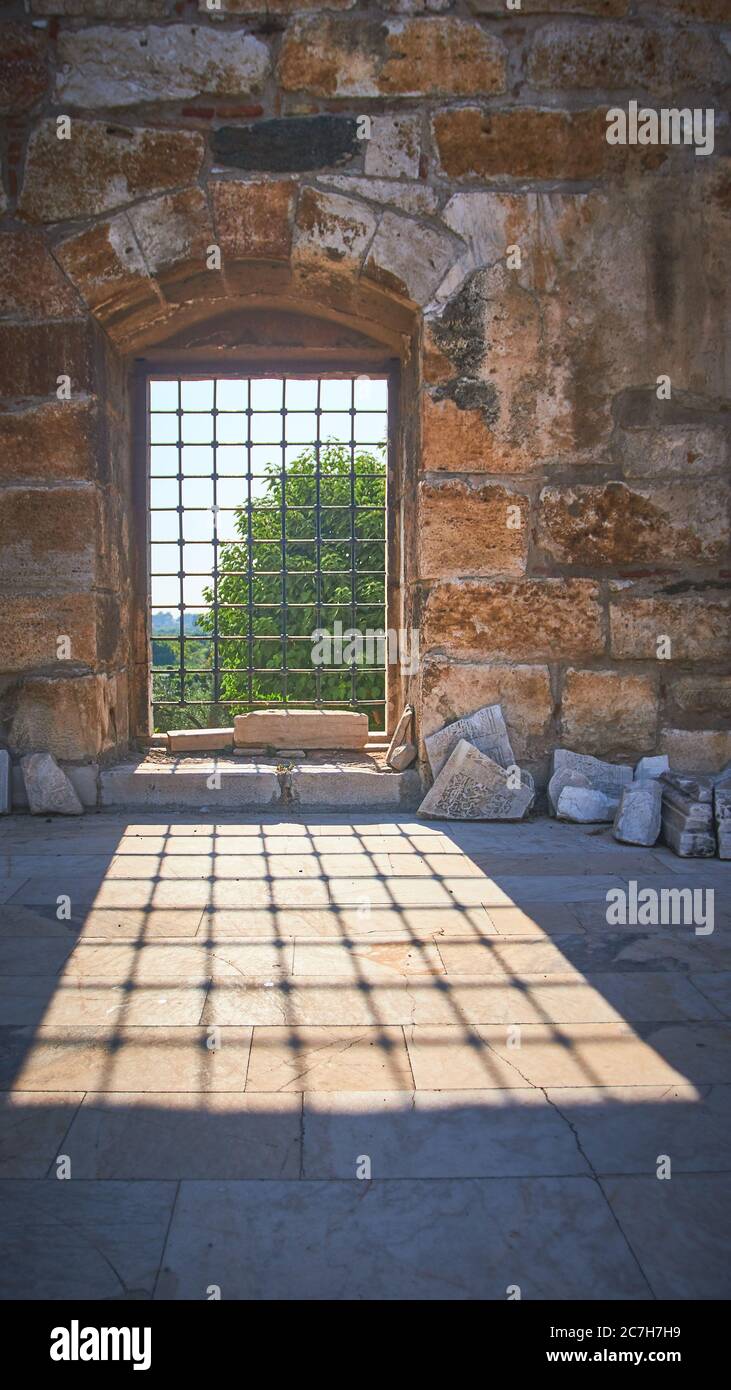 Vertical shot of a window with metal bars casting a shadow at daytime ...