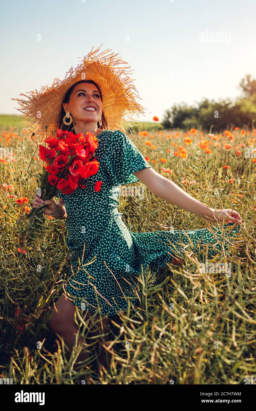 Portrait of woman gathered bouquet of poppies flowers walking in summer ...