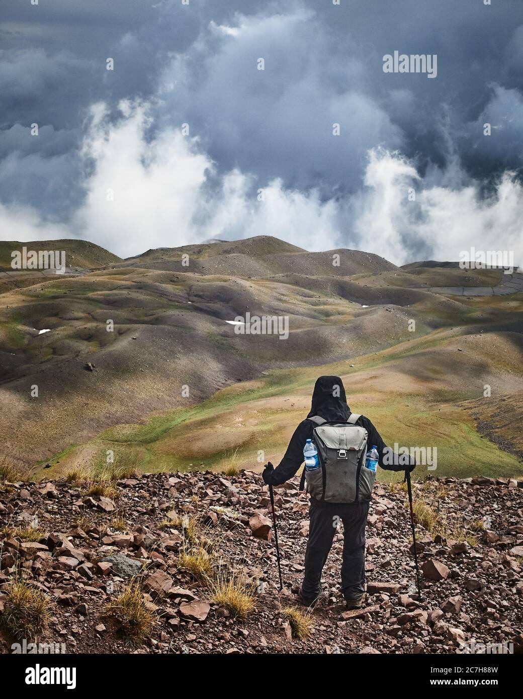 Vertical shot of a male standing on a hill while enjoying the view with ...