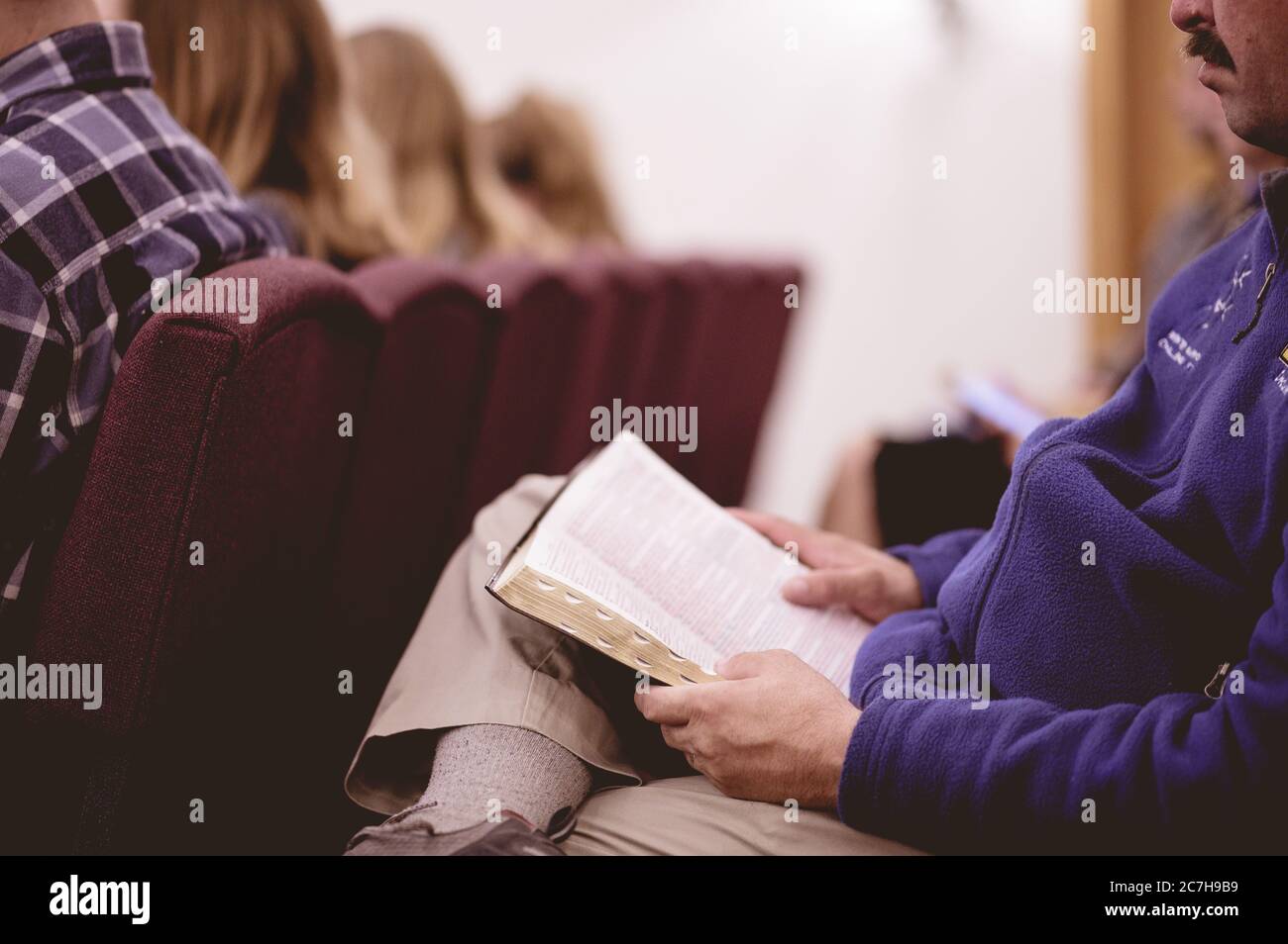 Person sitting on a chair and reading a book around other people Stock ...