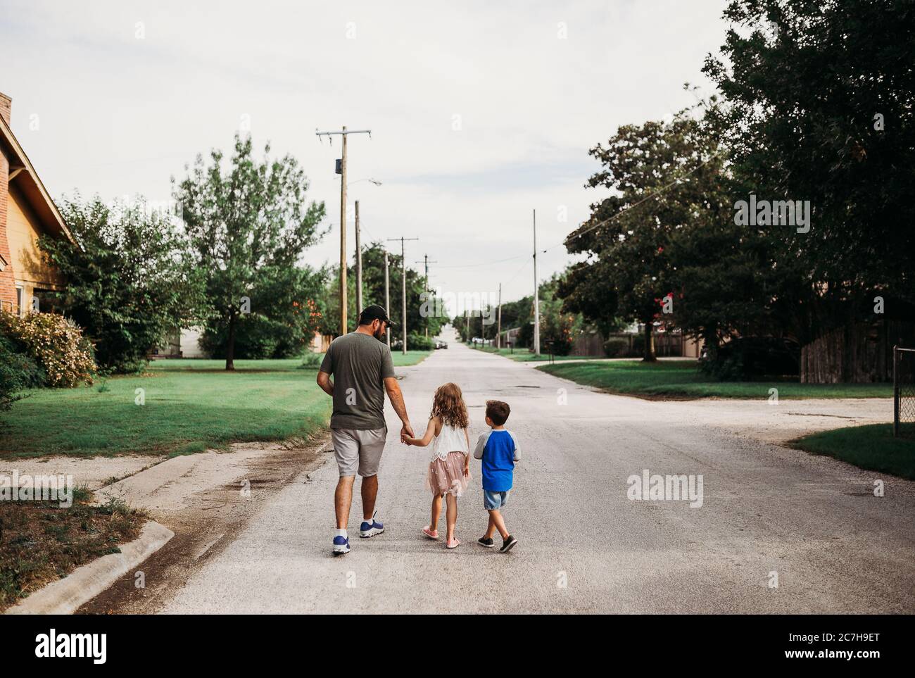 Dad and two young kids going on a walk in neighborhood Stock Photo - Alamy