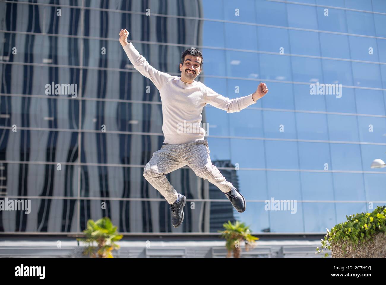Successful young man in work environment very happy jumping Stock Photo ...