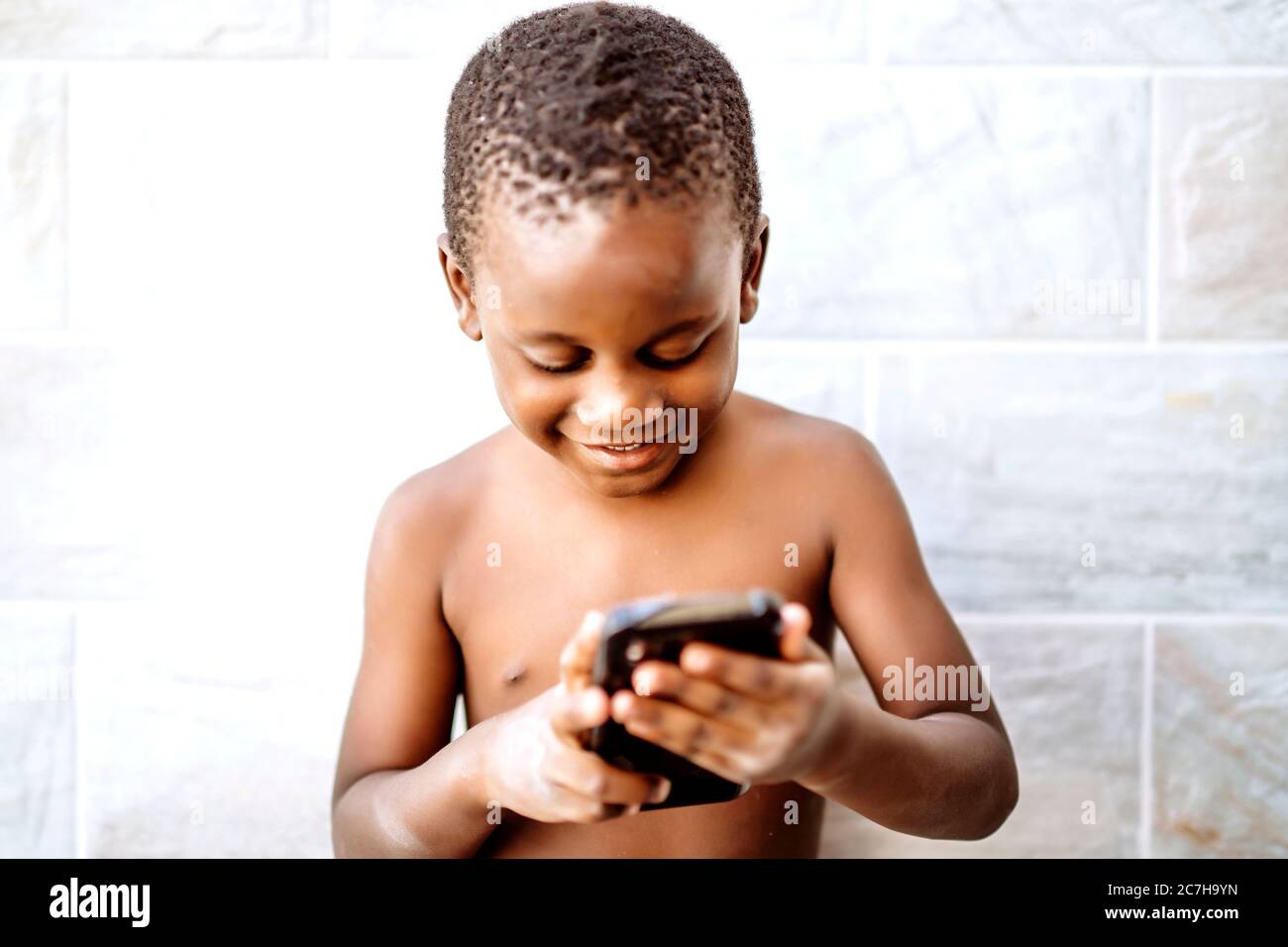 Nice african boy has fun using a mobile phone Stock Photo - Alamy