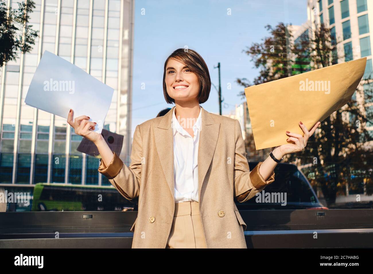 Young joyful businesswoman holding envelope with response happily ...