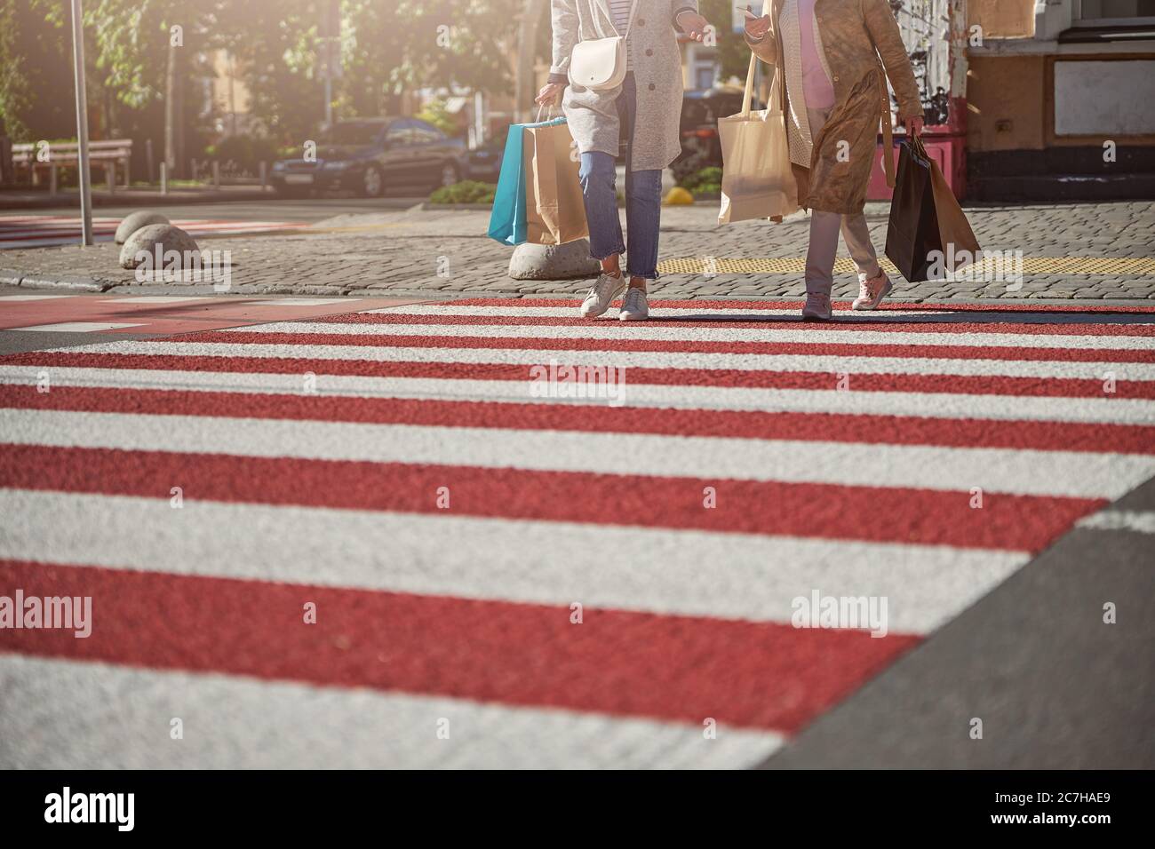 Two people walking across the road on the pedestrian crossing Stock ...