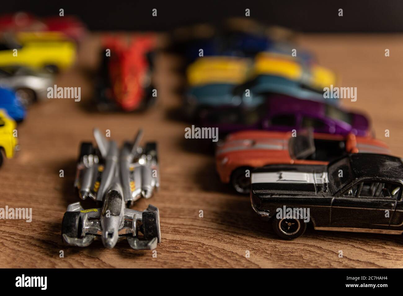 Selective focus shot of a toy sports car near other cars on a wooden ...