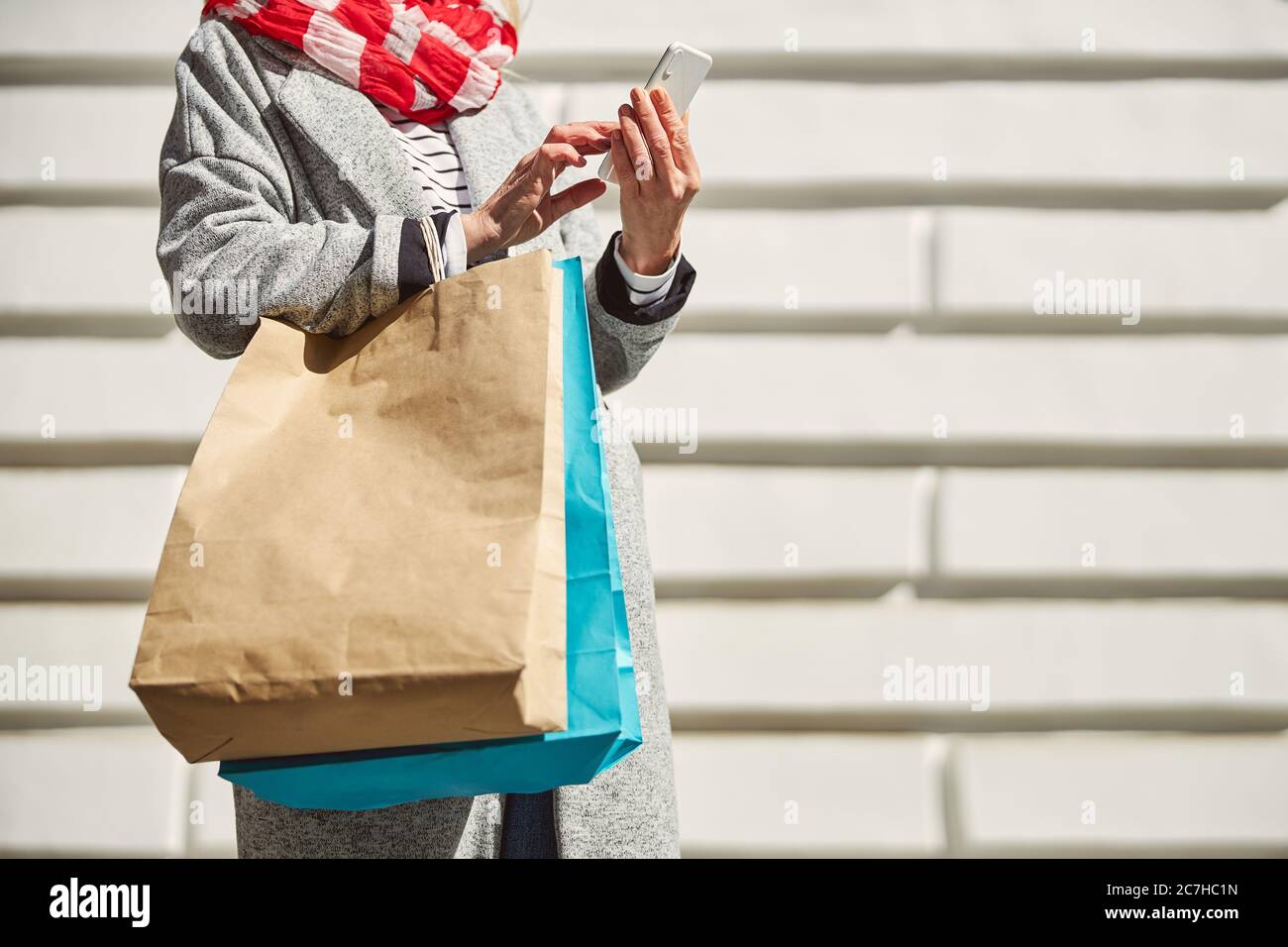 Female holding paper packets in hand while using smartphone Stock Photo ...