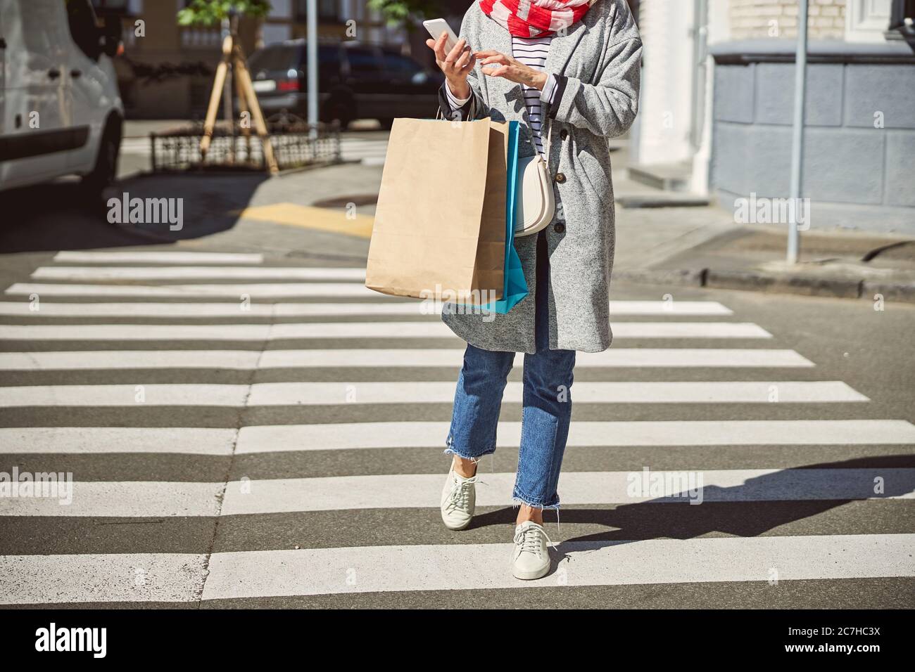 Woman walking along the street with paper shopping bags Stock Photo - Alamy