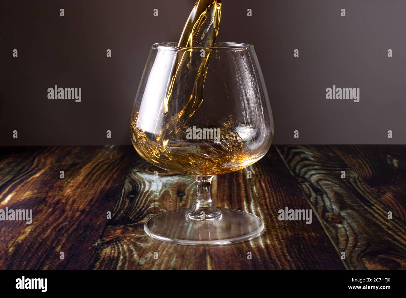 Pouring cognac into the glass and spilling past the glass. Strong ...