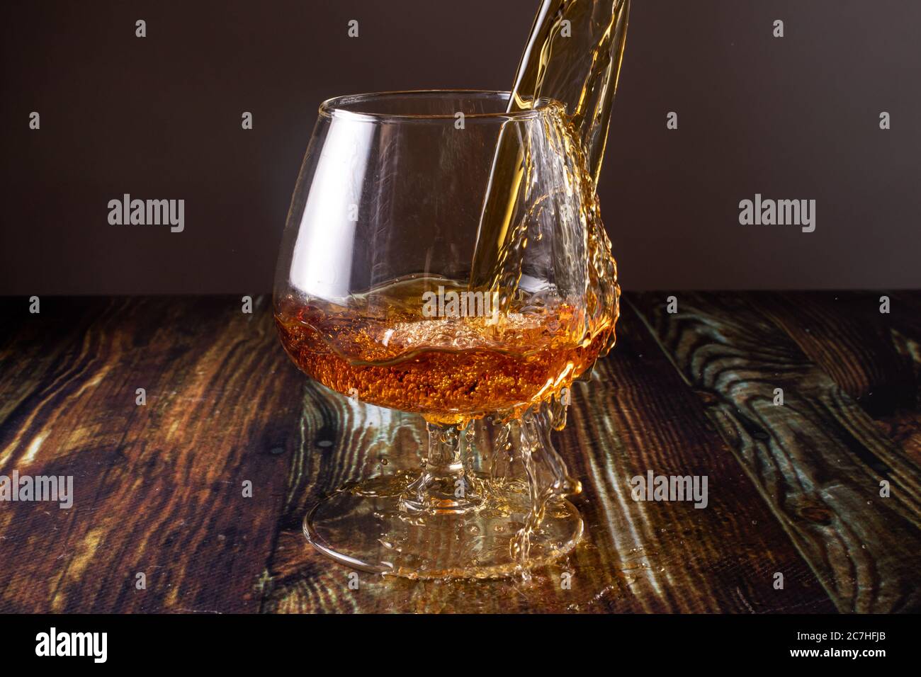 Pouring cognac into the glass and spilling past the glass. Strong ...