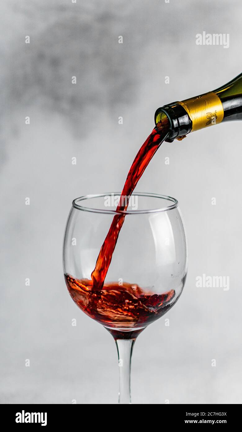 Vertical closeup shot of red wine being poured into a wine glass with ...