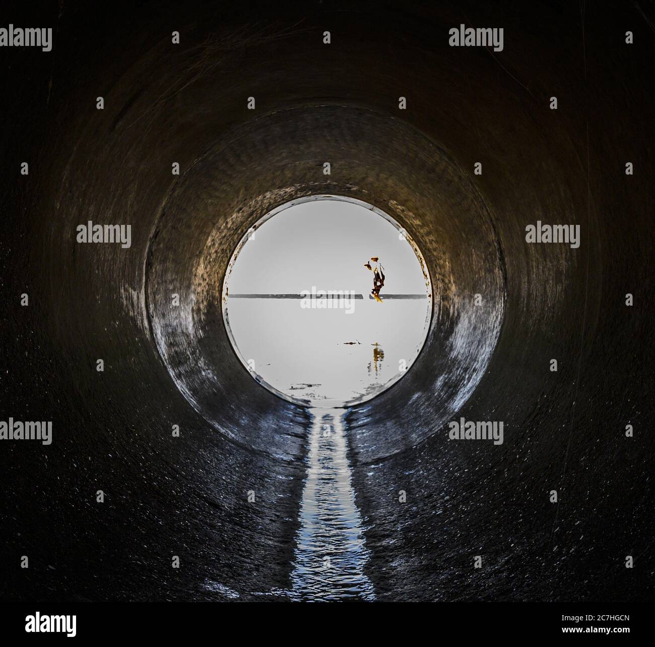 Look form a pipe looking at the beach surrounded by the sea with people ...