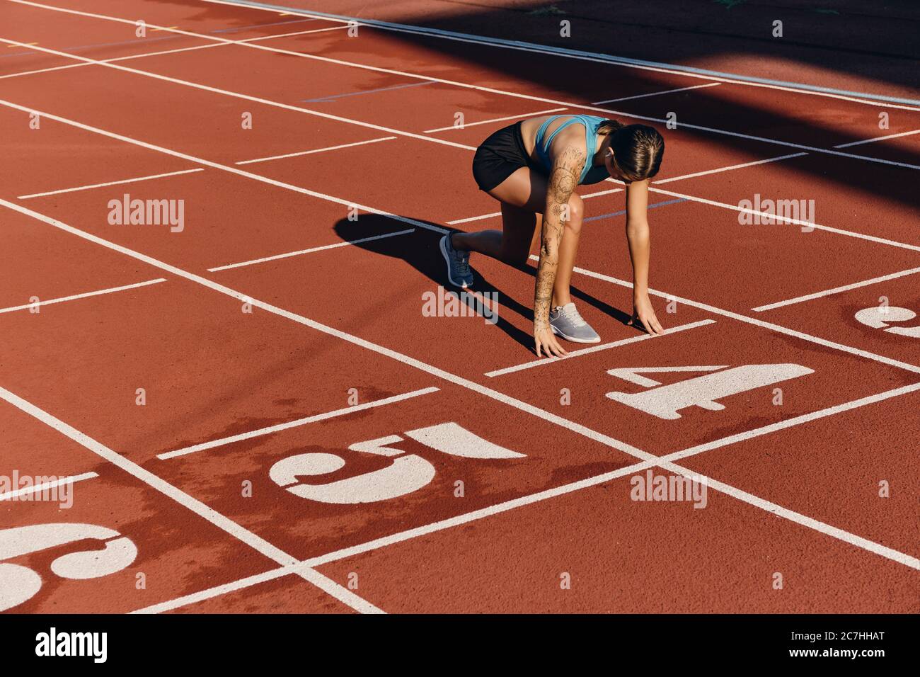 Confident athlete girl in sportswear standing in starting position ...