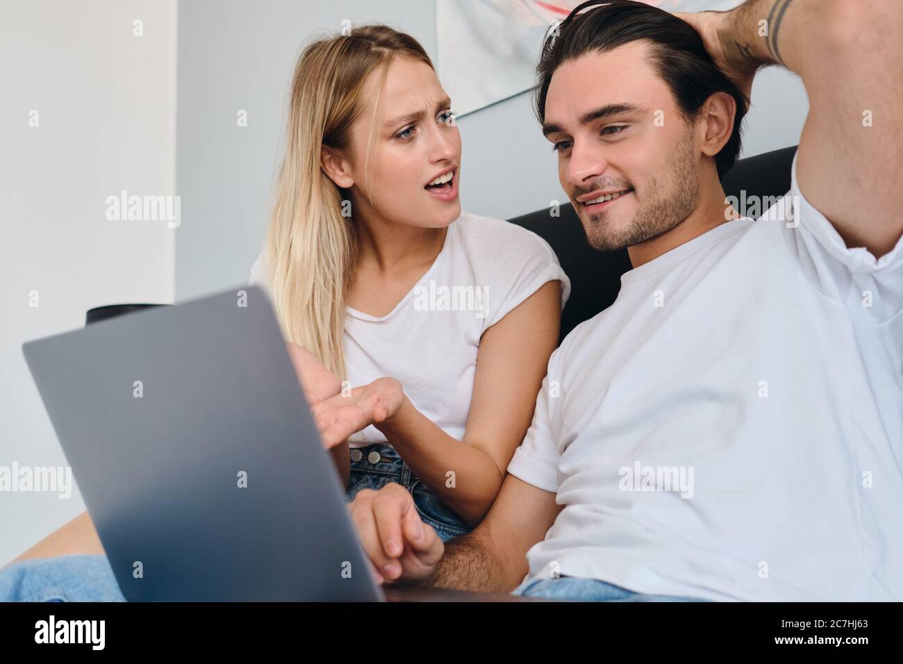 Young blond woman amazedly looking at smiling brunette man happily ...